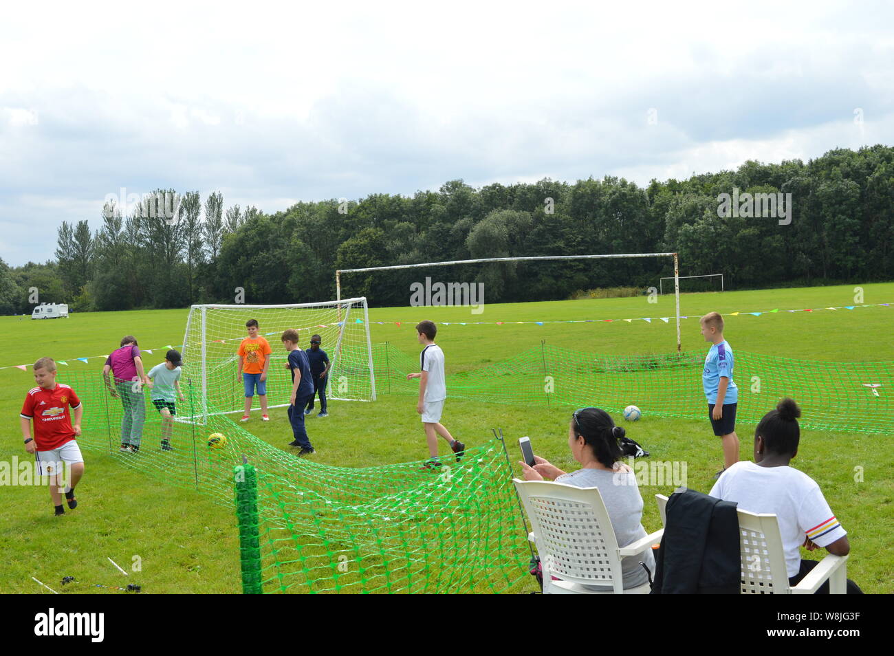 Parent watching their Kids playing football Stock Photo - Alamy