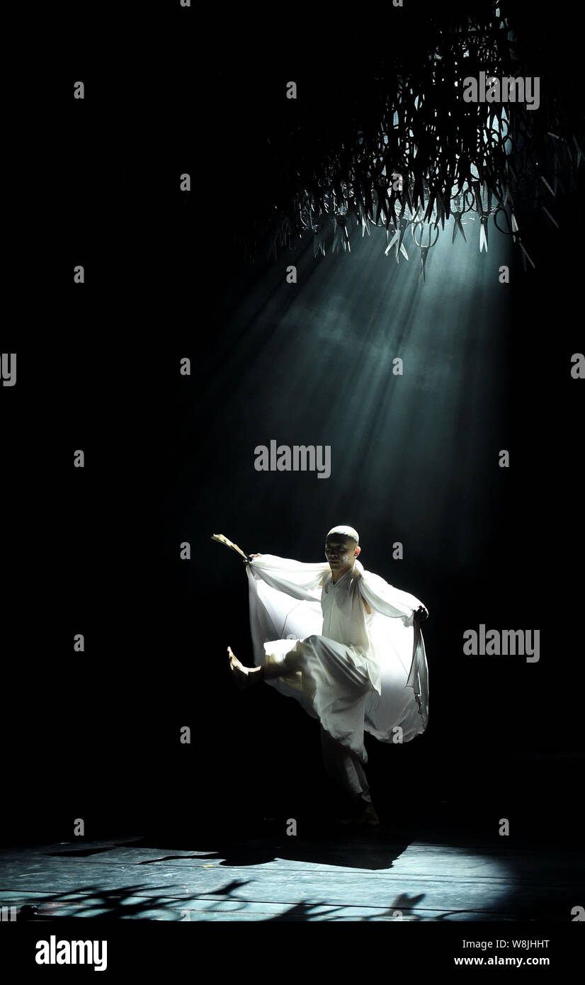 A dancer performs under thousands of hanging scissors during the debut ...