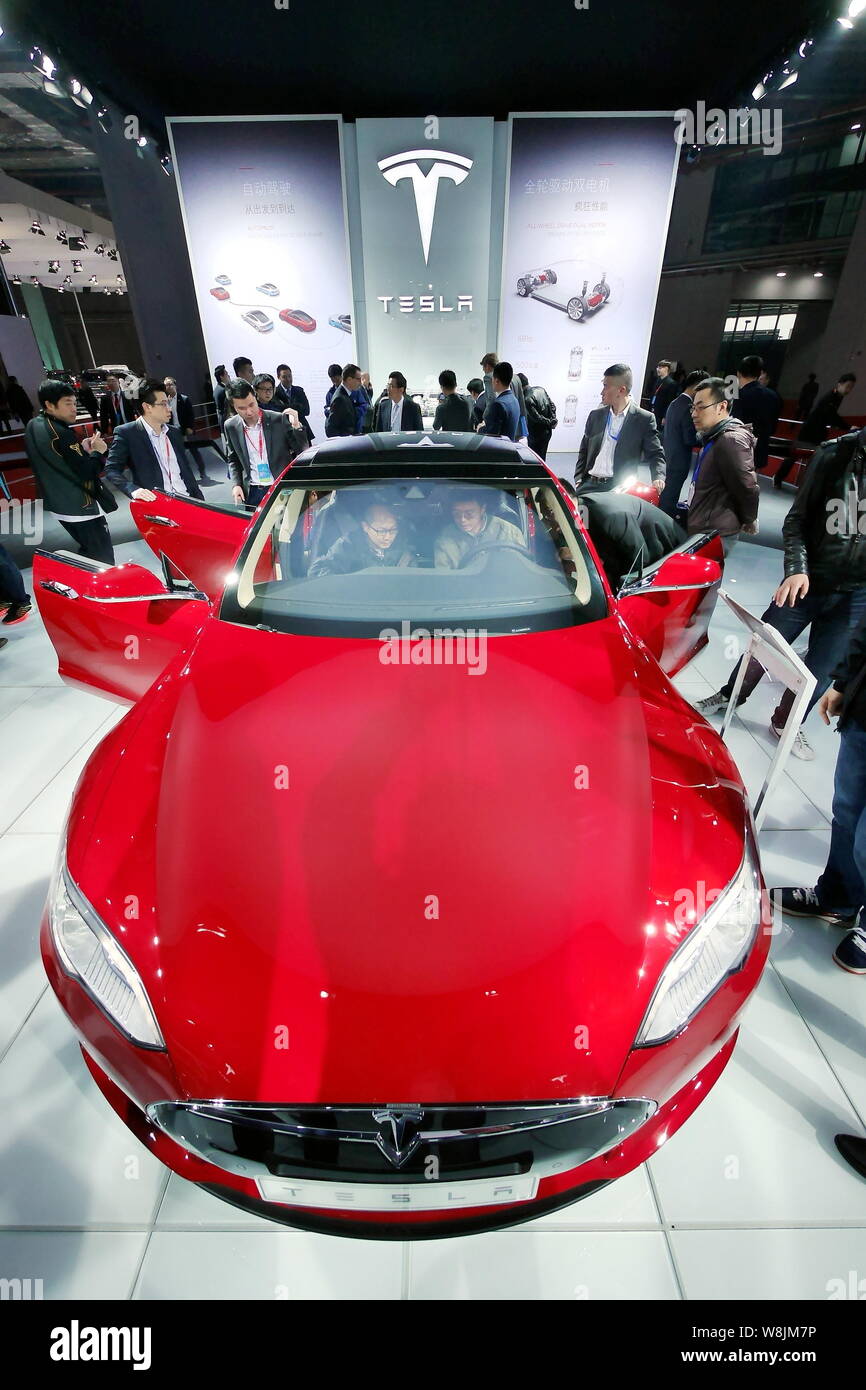 --FILE--Visitors try out or look at a Tesla Model S electric car on ...