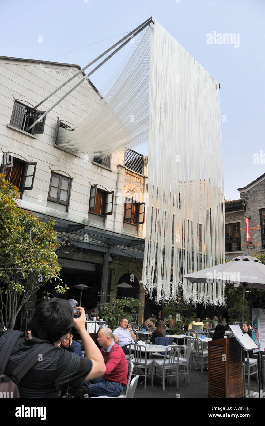 Tourists enjoy afternoon tea under an art installation during a shop ...