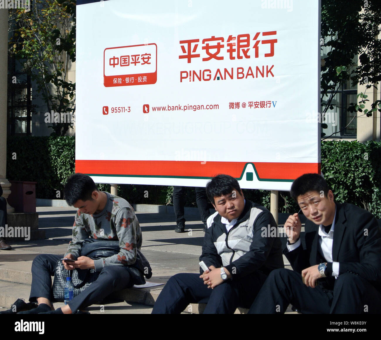 --FILE--Chinese visitors rest in front of an advertisement of Ping An ...