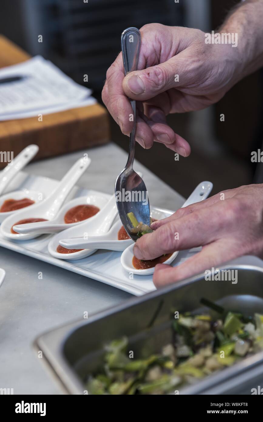 Vertical shot of a person's hand with a spoon putting ketchup in white ...