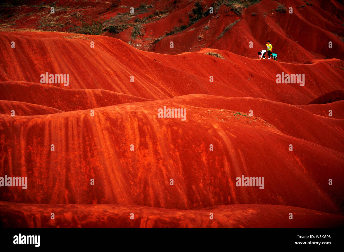 Children walk on red earth and brown-yellow silt in the Nanling ...