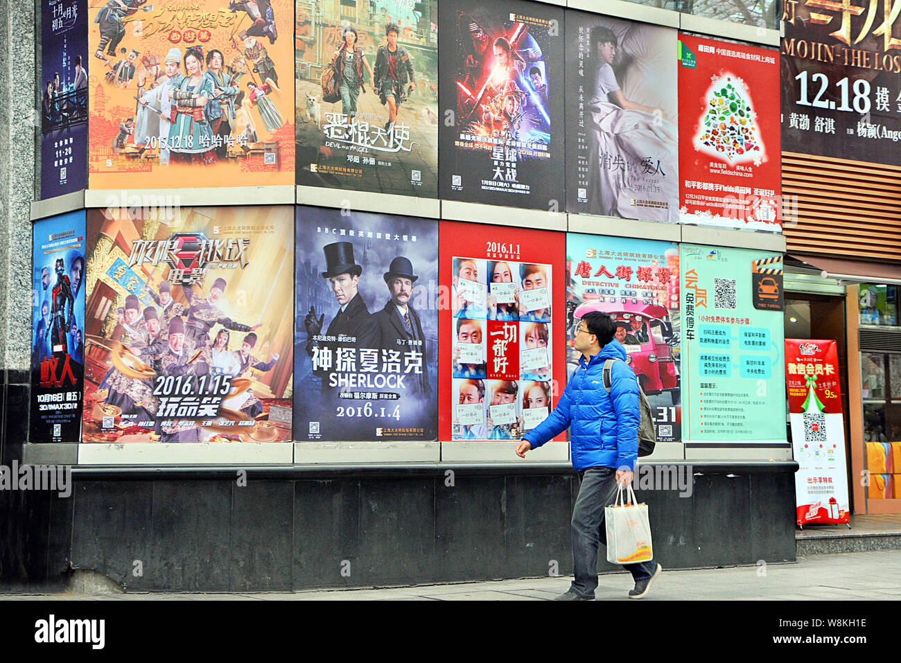 --FILE--A pedestrian walks past posters of movies at a cinema in ...
