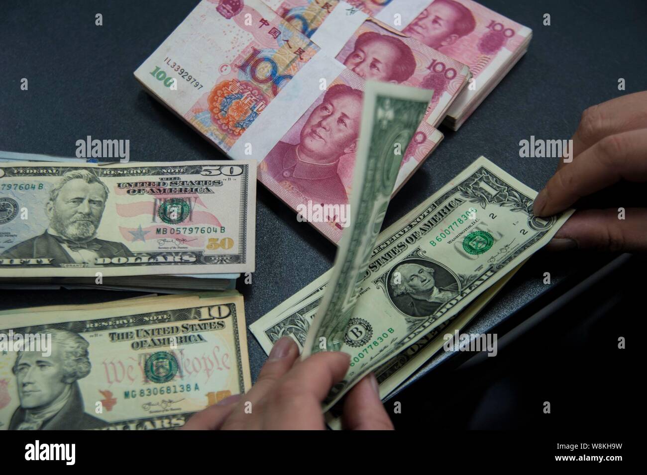 --FILE--A Chinese clerk counts US dollar notes next to RMB (renminbi ...