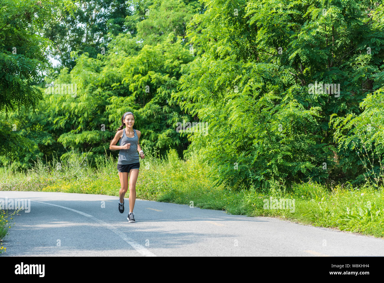Running girl runner jogging on nature park path during summer training ...