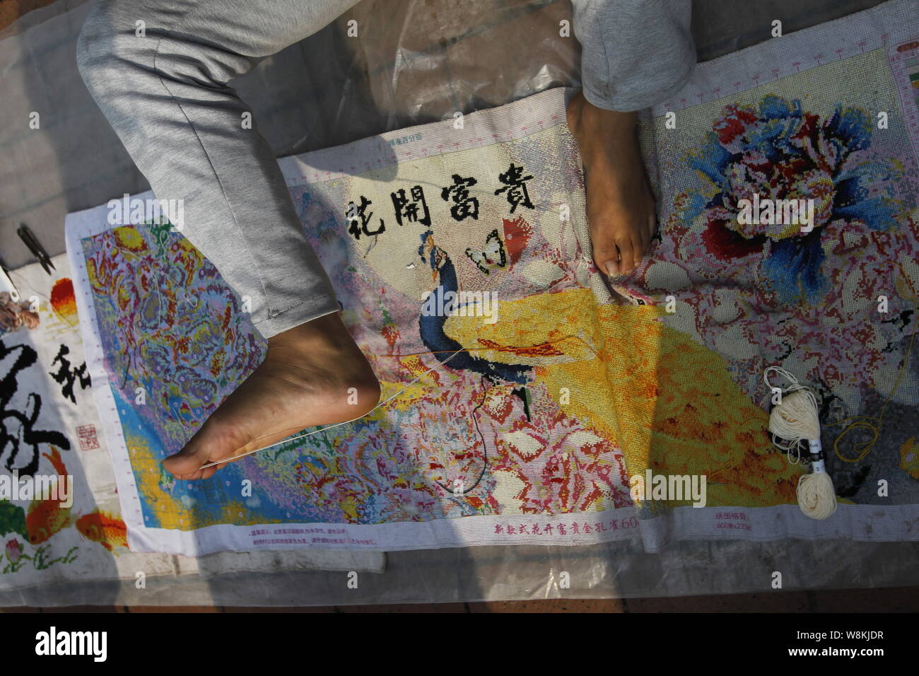 Armless Chinese man Xiaolou makes a cross-stitching work with his toes ...