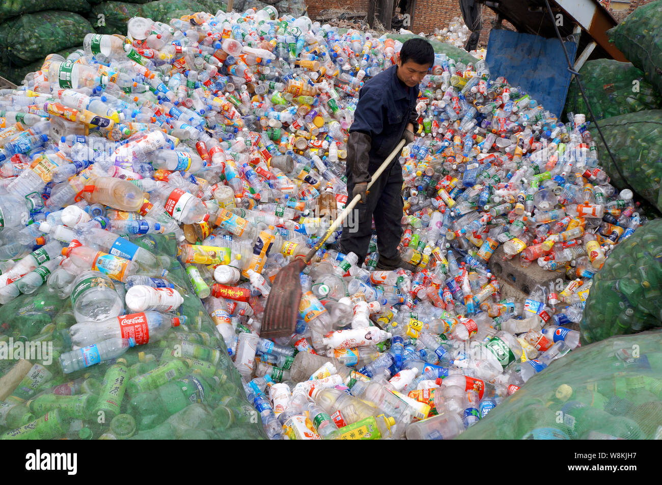 --FILE--A Chinese worker piles up discarded plastic bottles at a ...