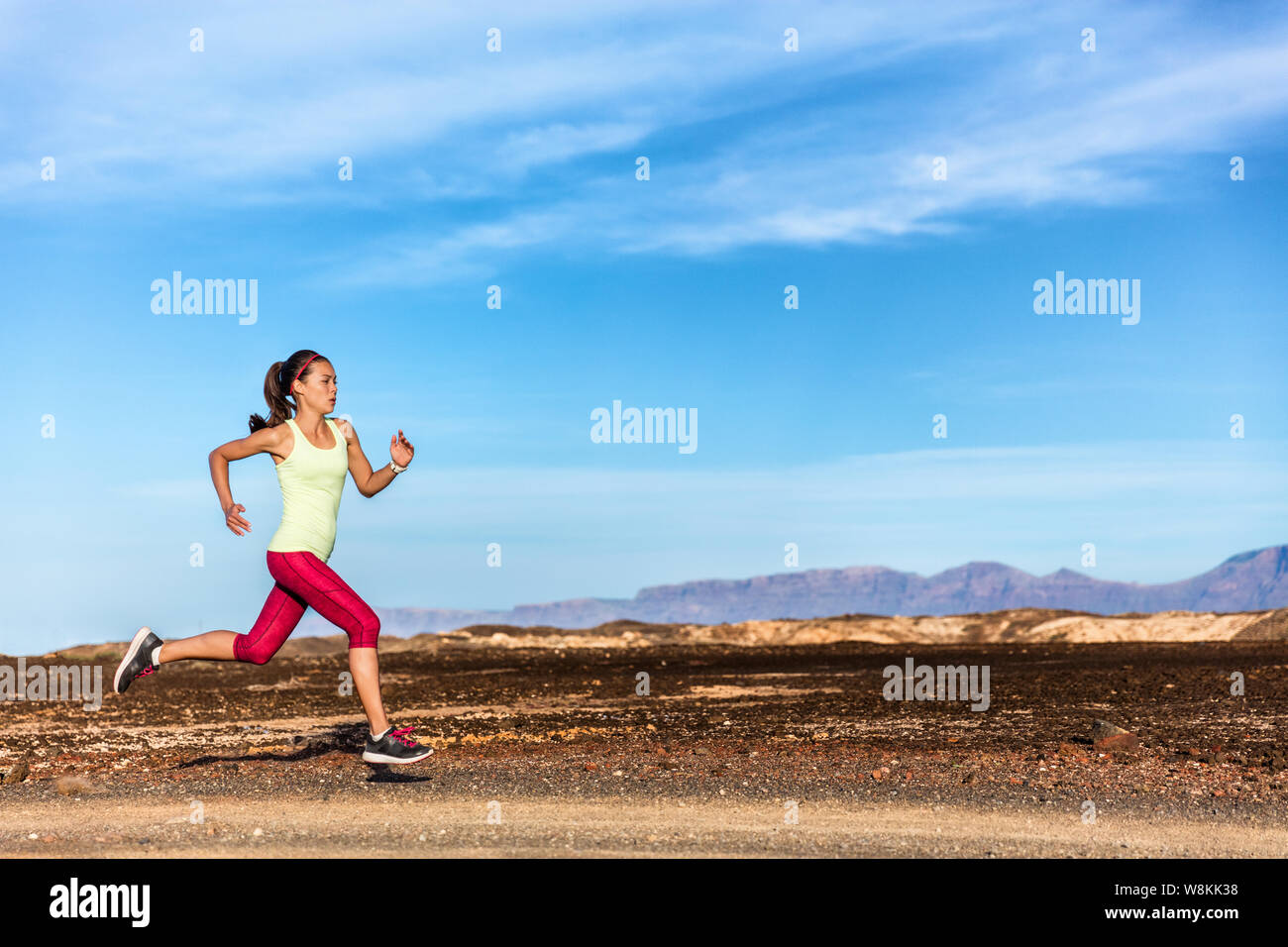Trail runner female athlete running in nature rocky mountain background ...