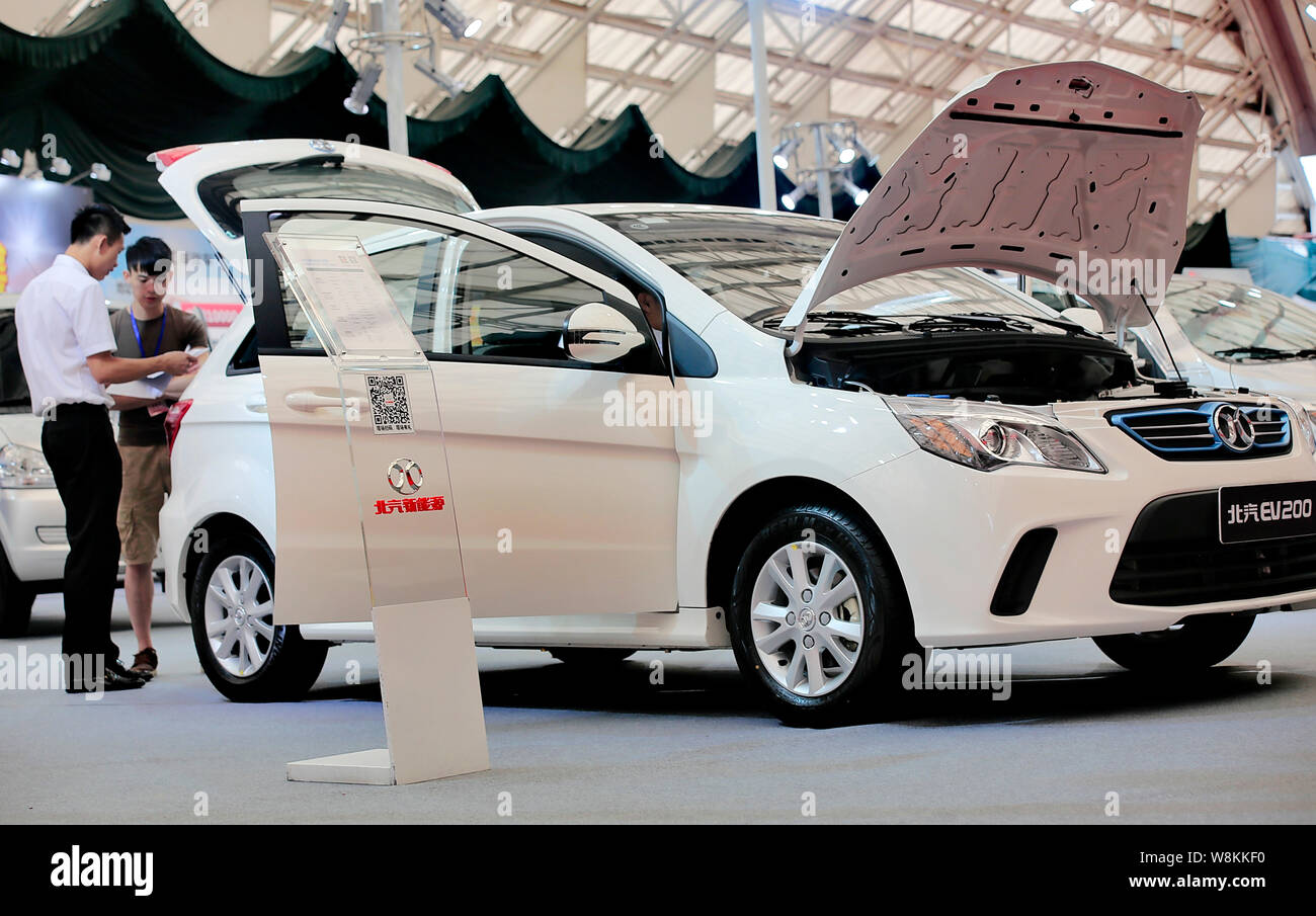 --FILE--People talk next to an EV200 electric car of BAIC BJEV on ...