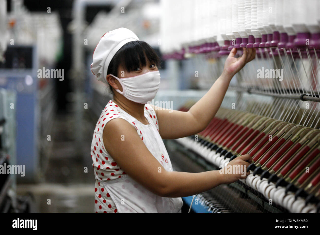 --FILE--A Chinese worker handles production of yarn to be exported to Europe at a textile ...