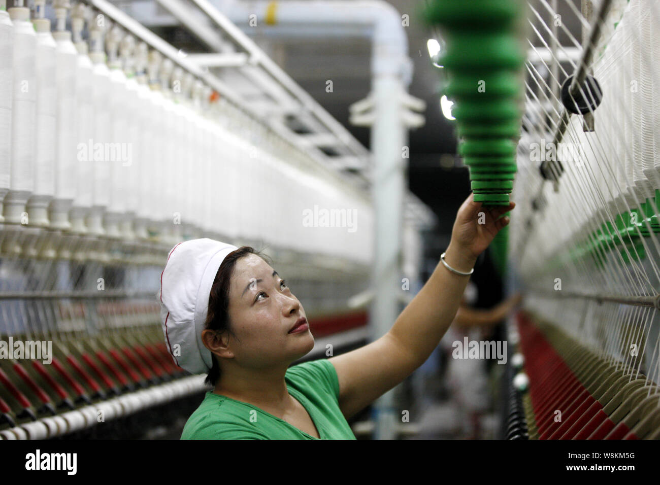 --FILE--A Chinese worker handles production of yarn to be exported to Europe at a textile ...