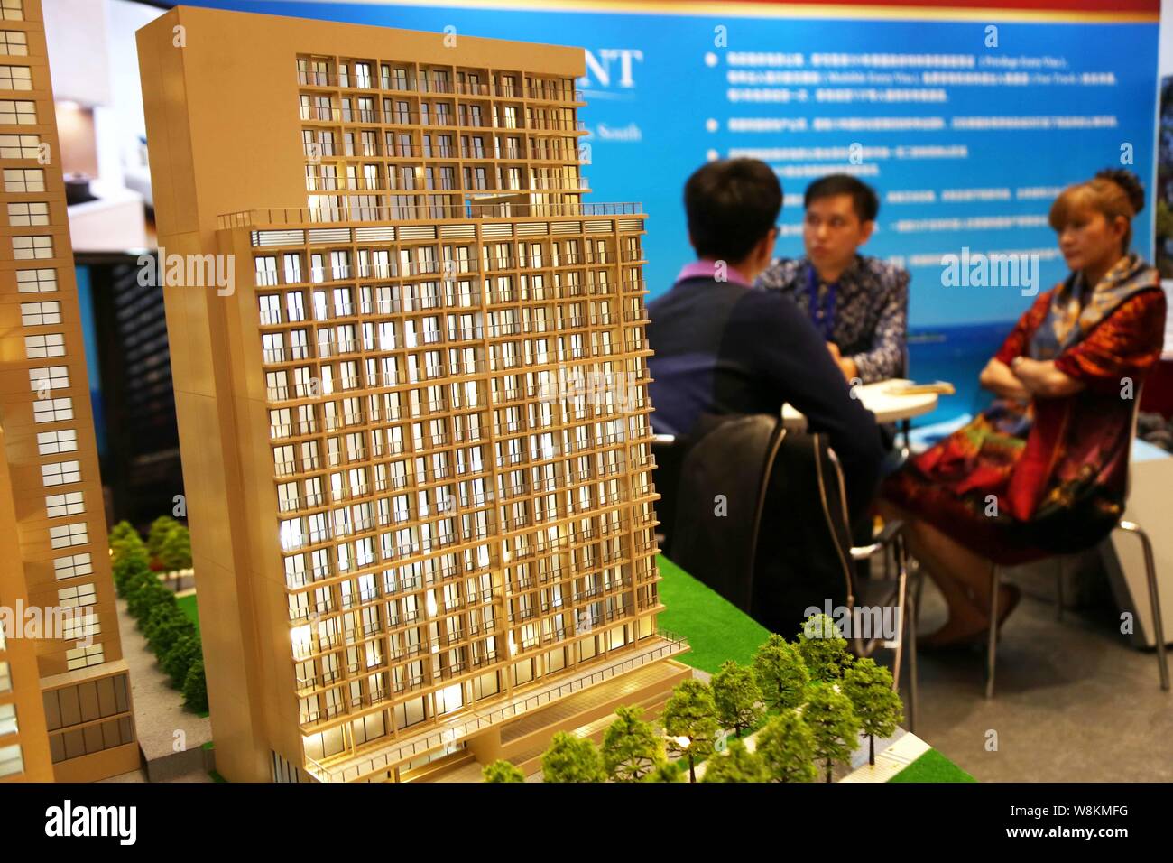 Chinese homebuyers sit next to models of residential buildings during a ...