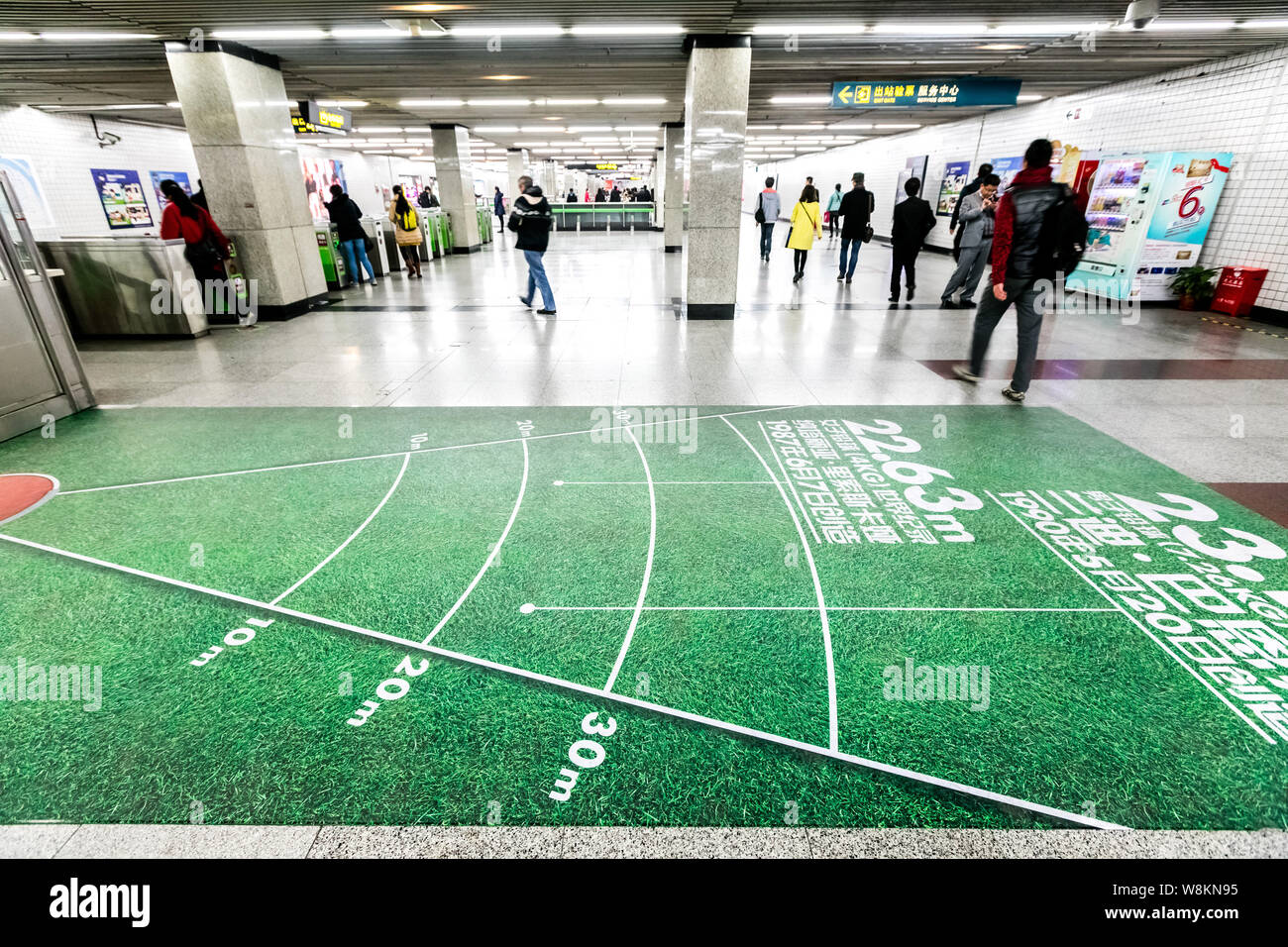 Passengers walk over track-and-field-themed decorations on the floor ...