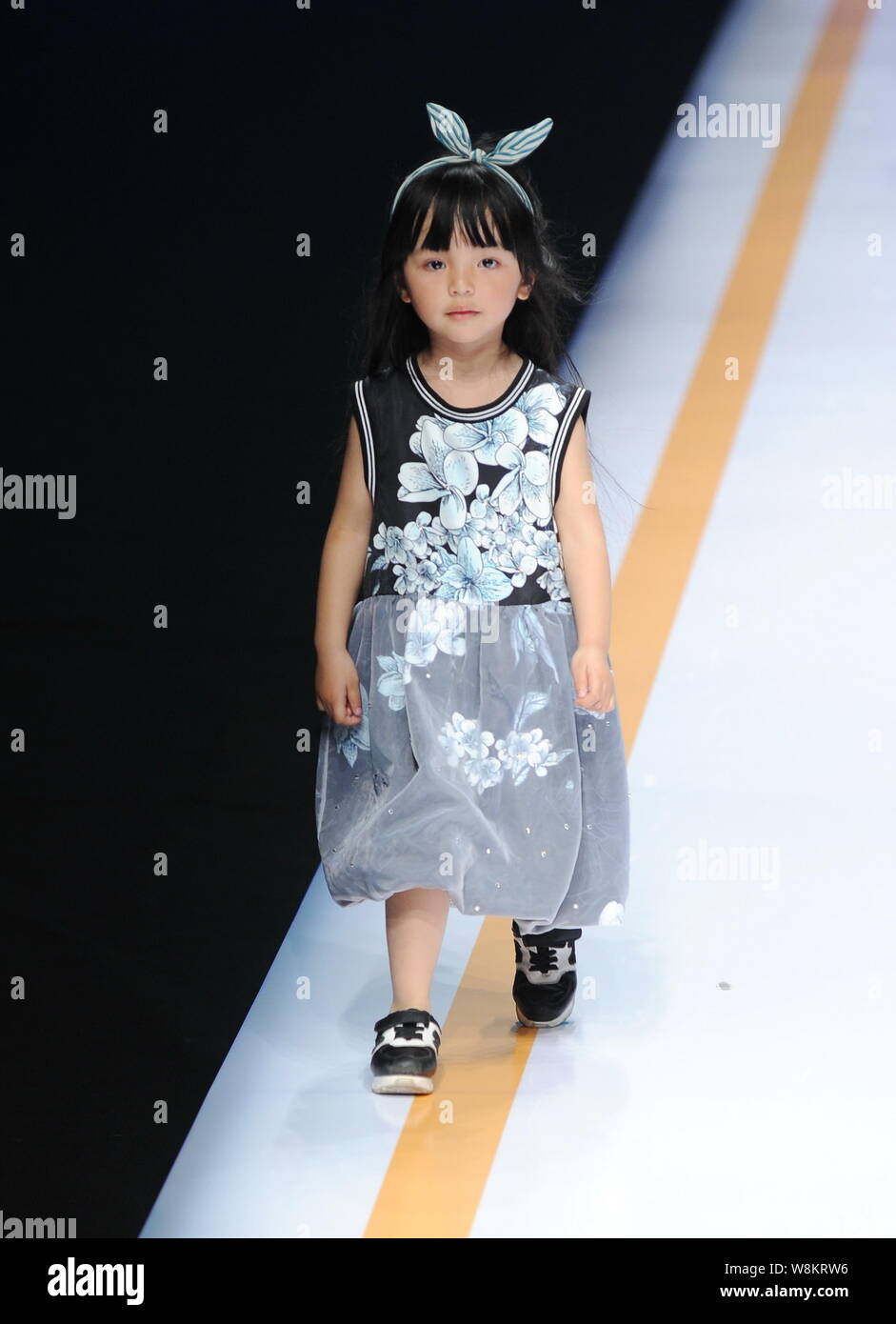 A child model displays a new creation at the fashion show of Comme Tu ...