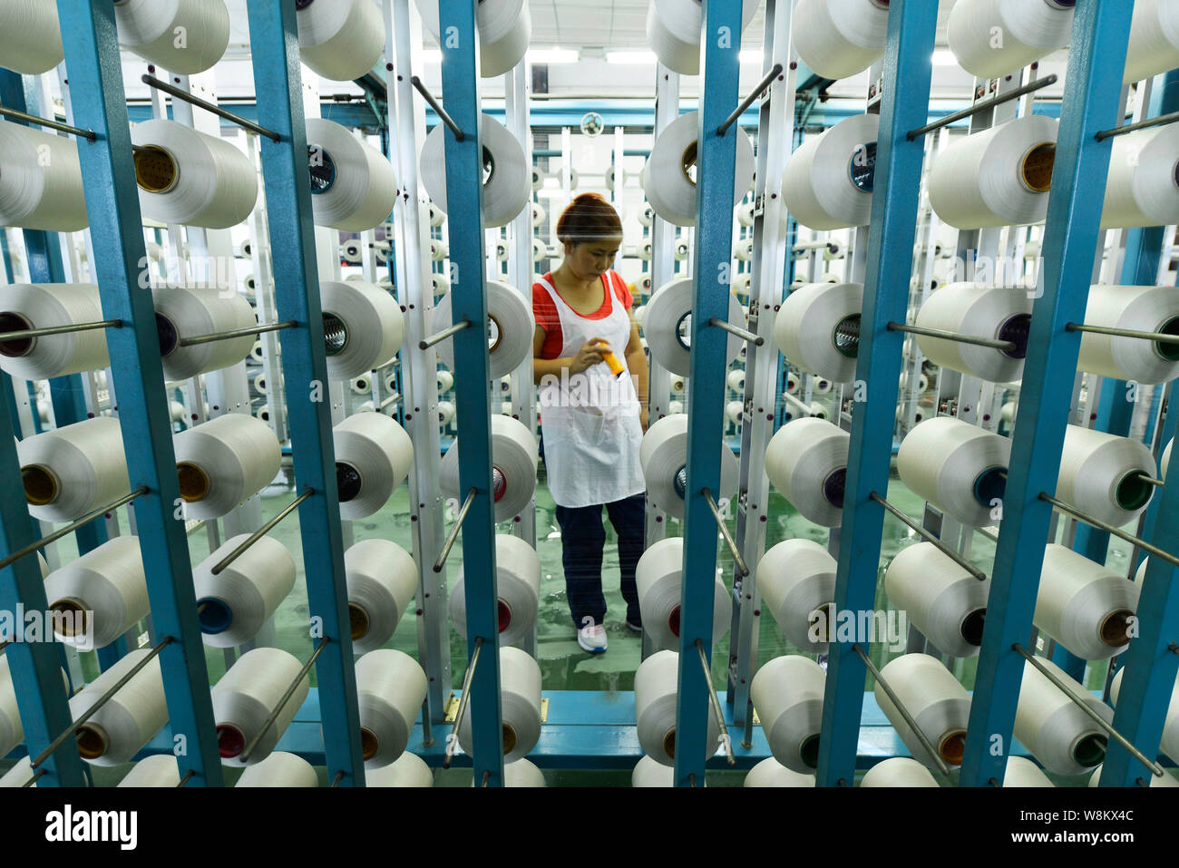 --FILE--A female Chinese worker handles production of yarn at a textile factory in Megnshan ...