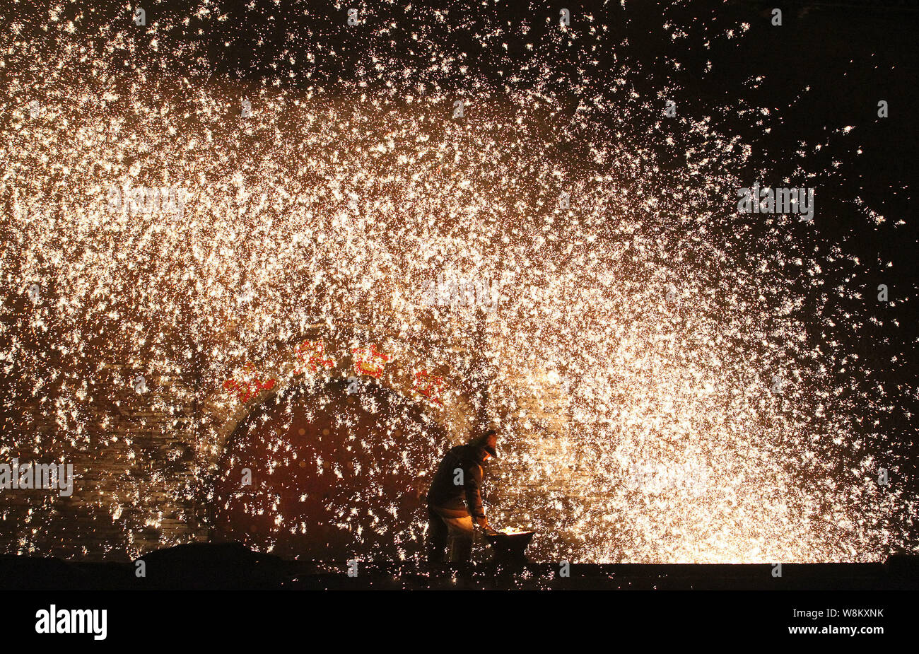 A Chinese blacksmith throws molten iron against a wall to create ...
