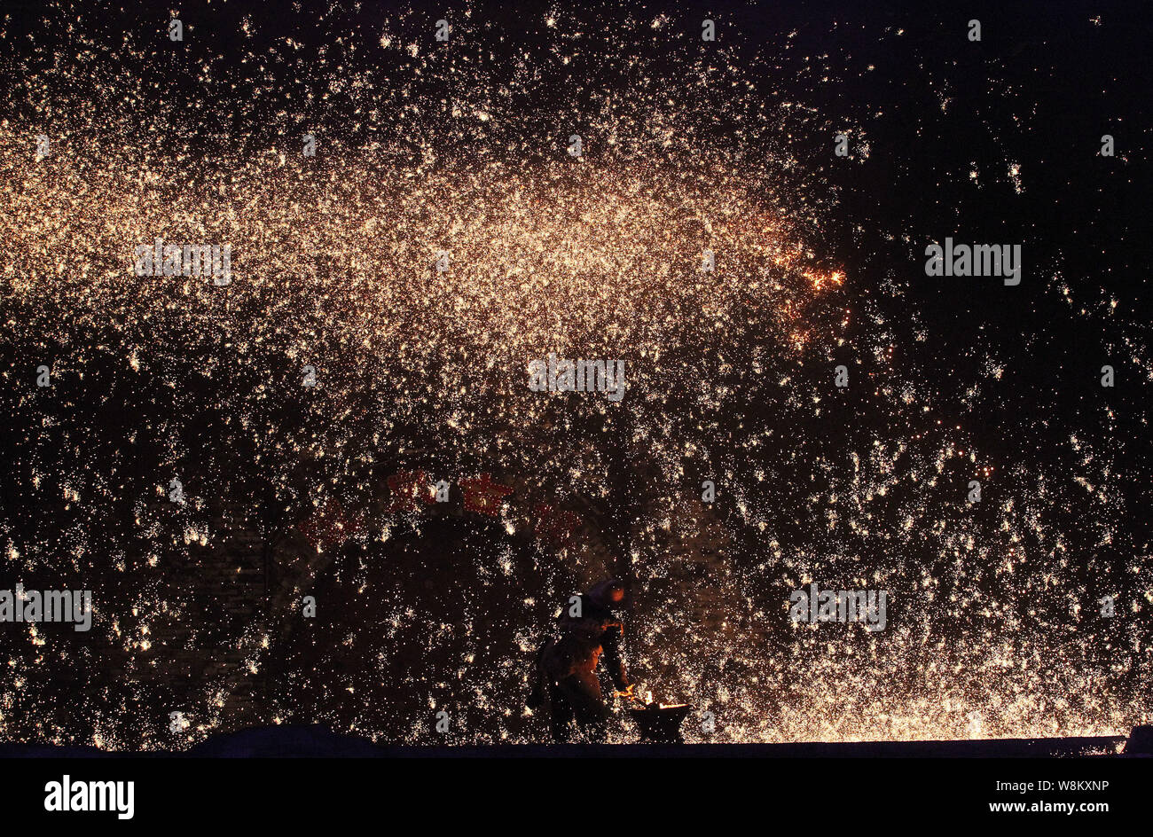 A Chinese blacksmith throws molten iron against a wall to create ...