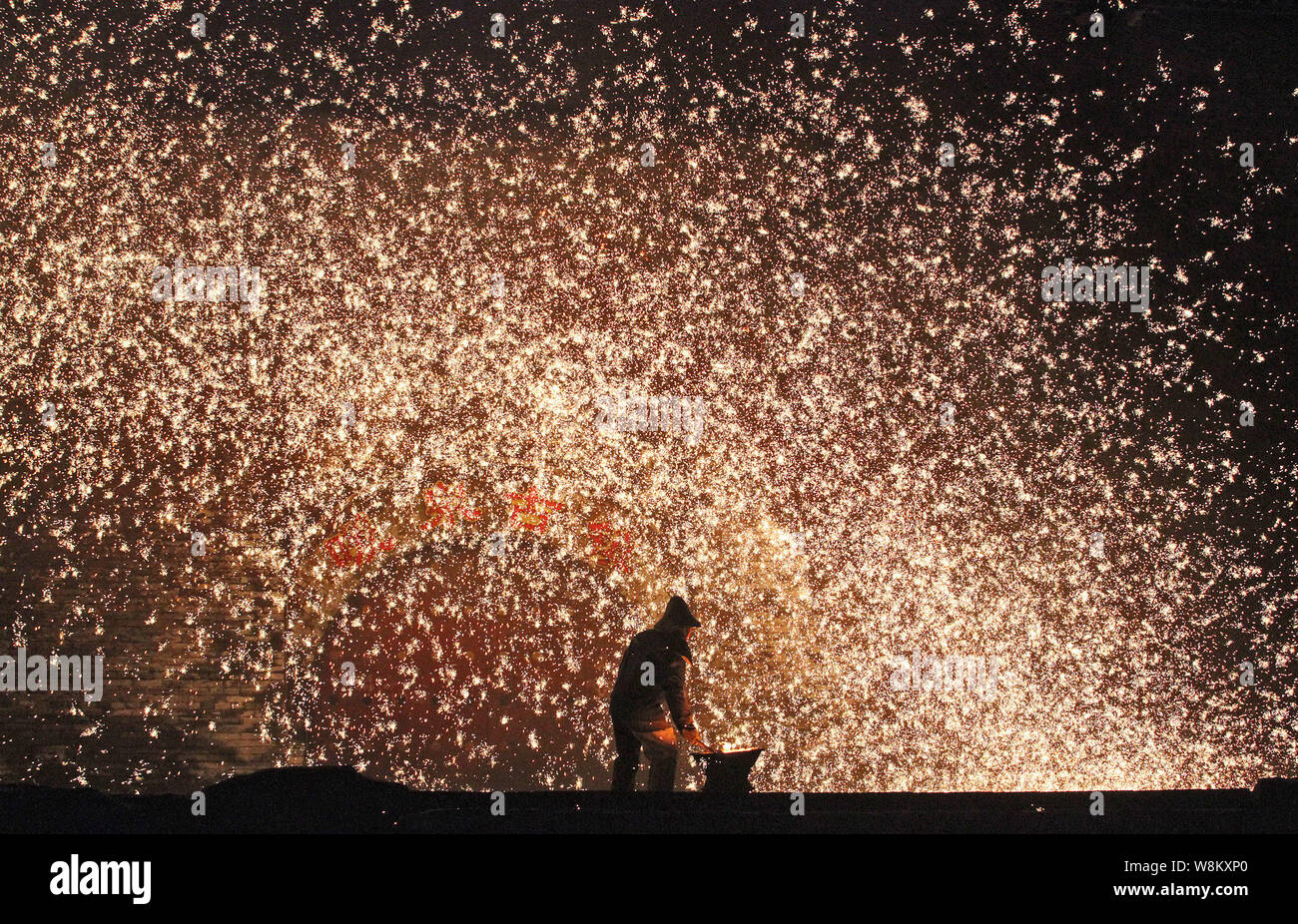 A Chinese blacksmith throws molten iron against a wall to create ...
