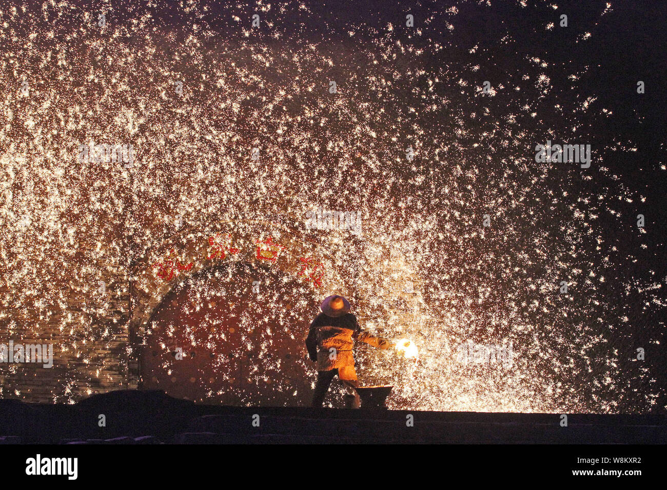 A Chinese blacksmith throws molten iron against a wall to create ...