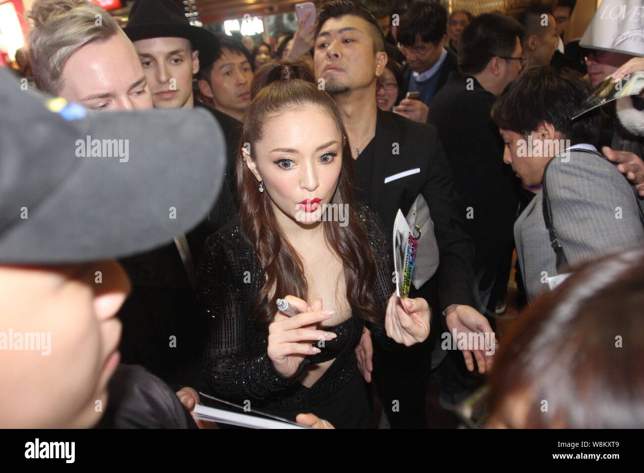 Japanese singer Ayumi Hamasaki, center, signs autographs for fans on a street before midnight in ...