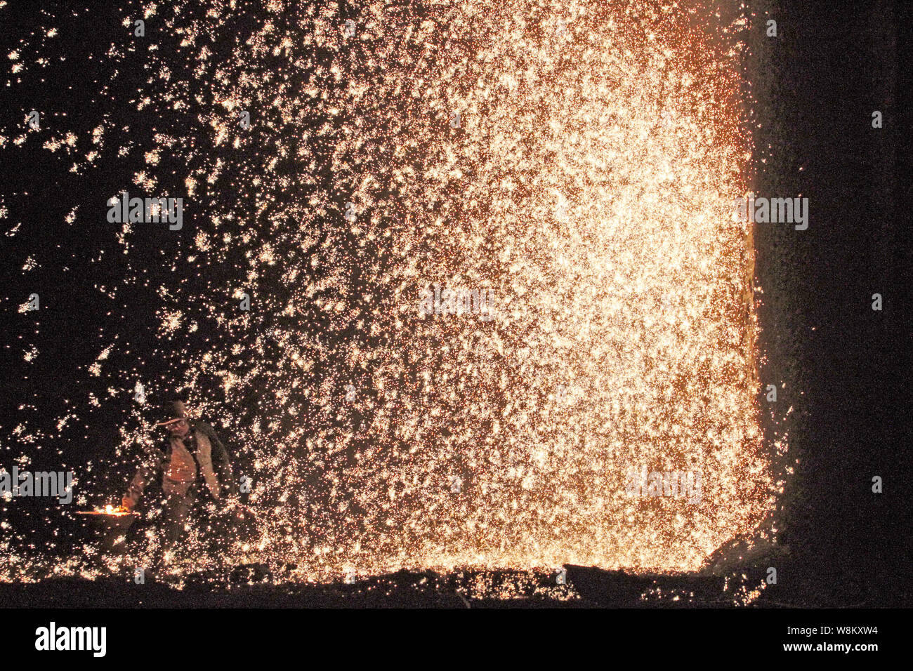 A Chinese blacksmith throws molten iron against a wall to create ...