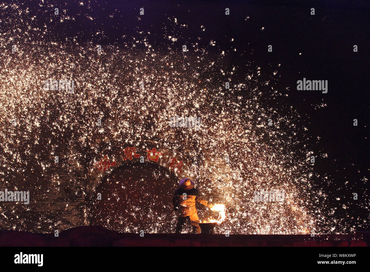 A Chinese blacksmith throws molten iron against a wall to create ...