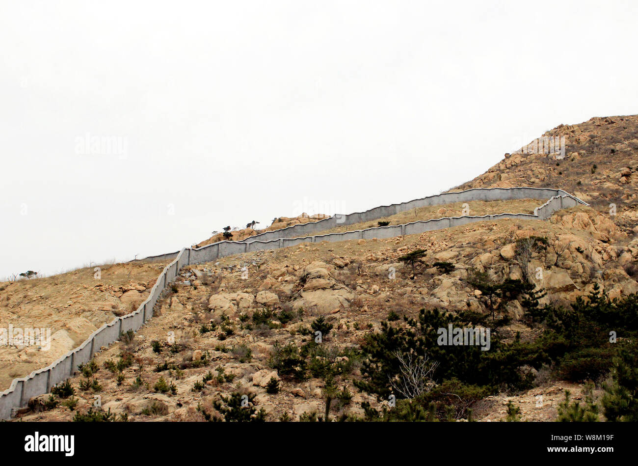 A long enclosing wall is built on the side of a mountain in east China ...