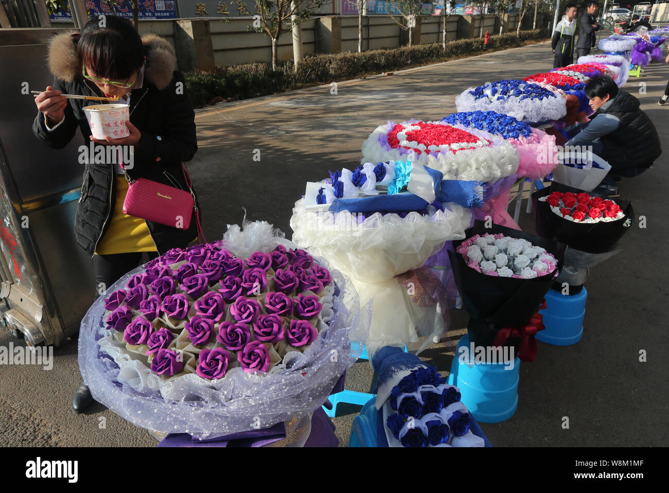 A flower trader eats lunch as she sells bouquets of flowers for ...