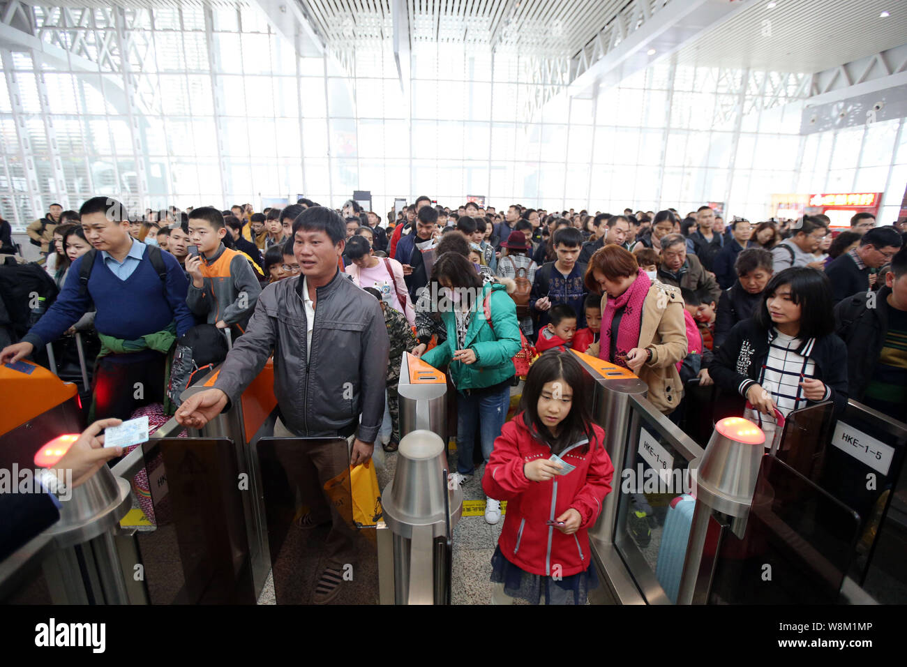 A crowd of Chinese passengers queue up to check in to take trains back ...