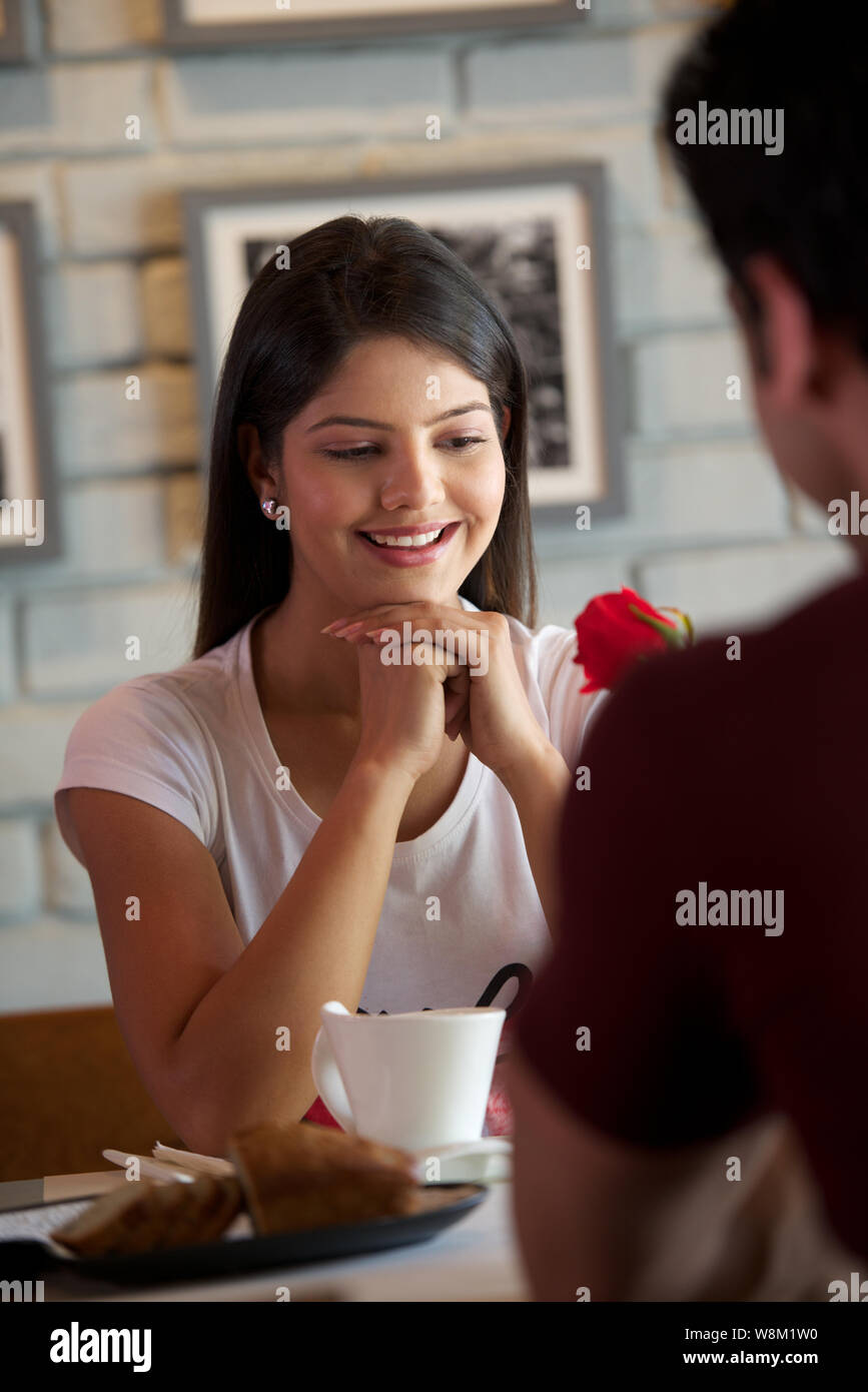 Man offering a rose to young woman in a restaurant Stock Photo - Alamy