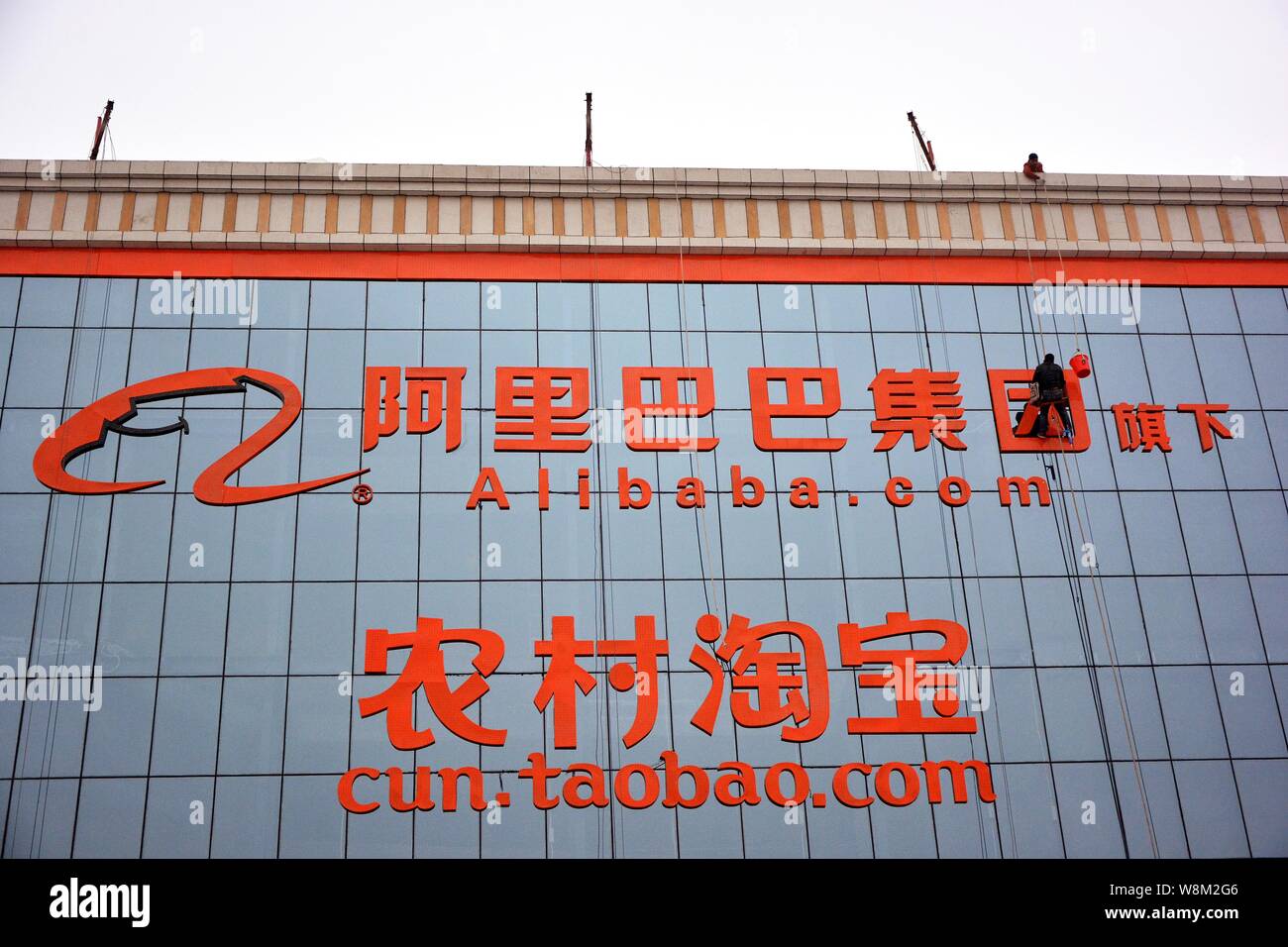 --FILE--A Chinese worker installs signs on the facade of the building ...