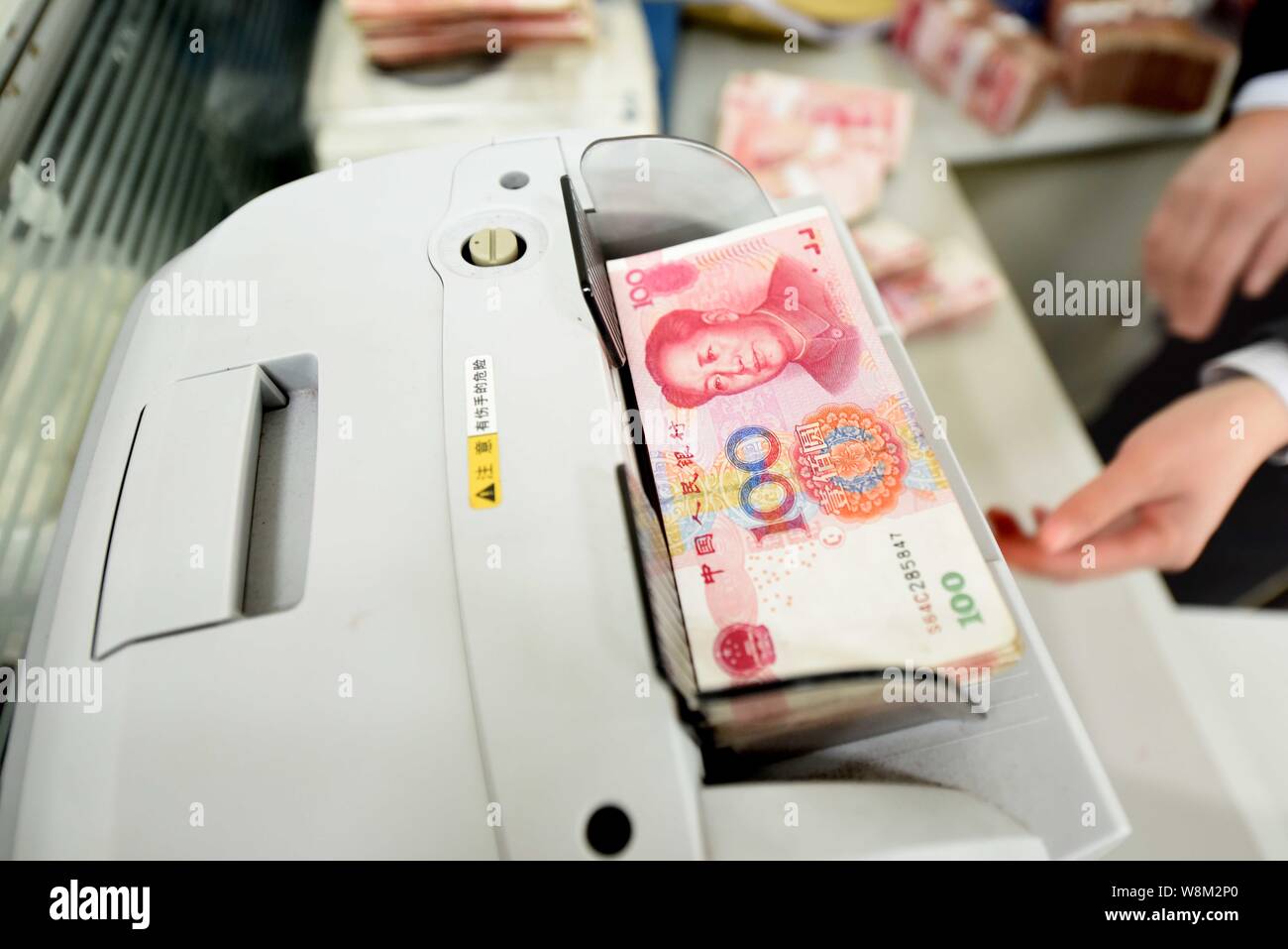 --FILE--A Chinese clerk uses a cash-counting machine to count RMB ...