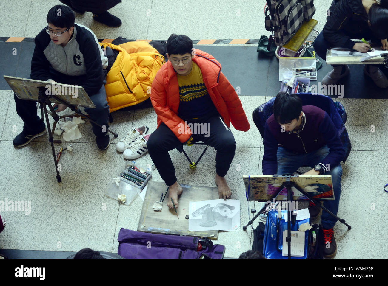 An armless Chinese candidate, center, draws with his feet amongst ...