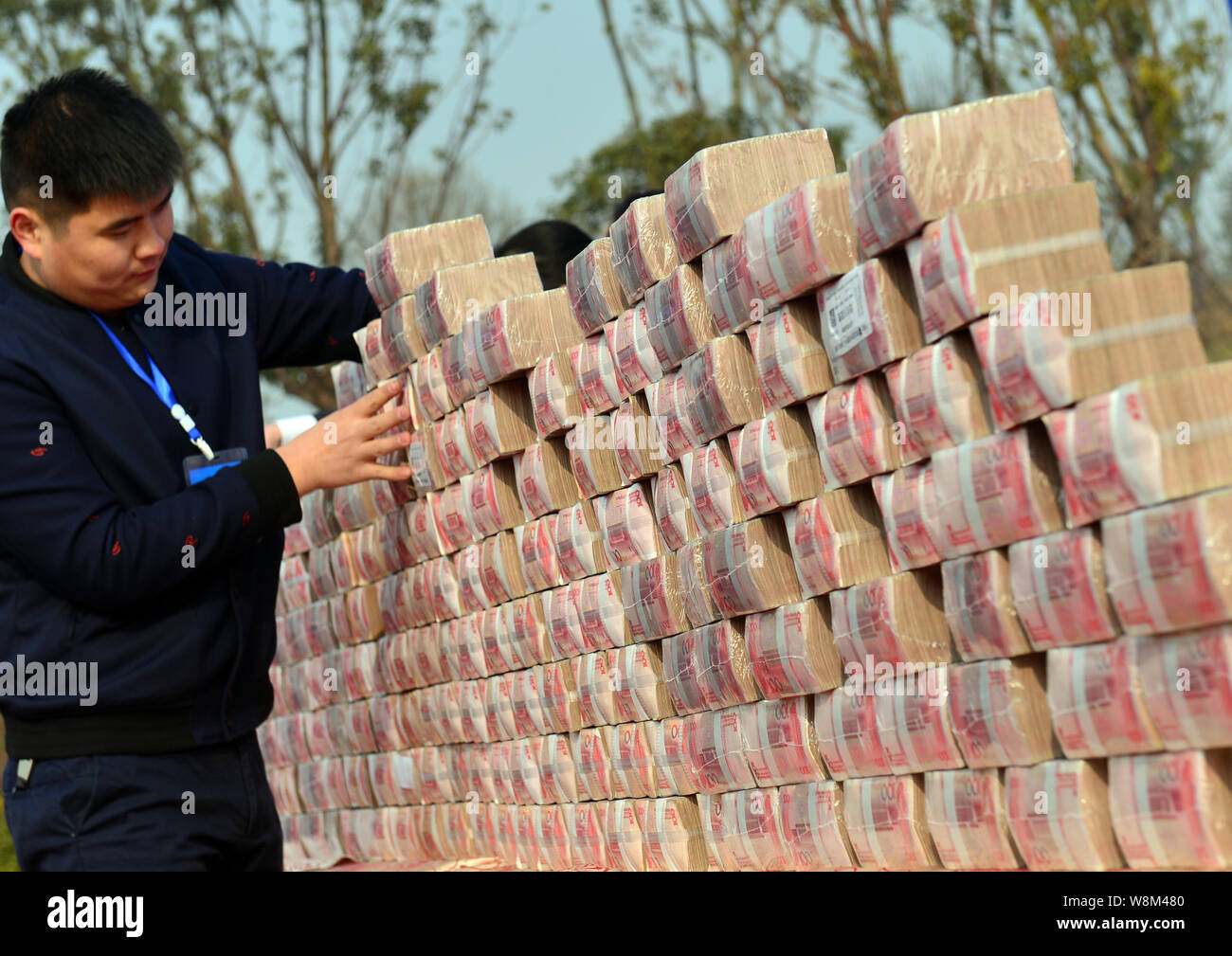 A Chinese employee prepares stacks of 100-yuan RMB (Renminbi) banknotes ...