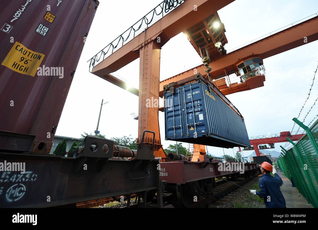 --FILE--A Chinese worker directs a crane to load a container onto a ...