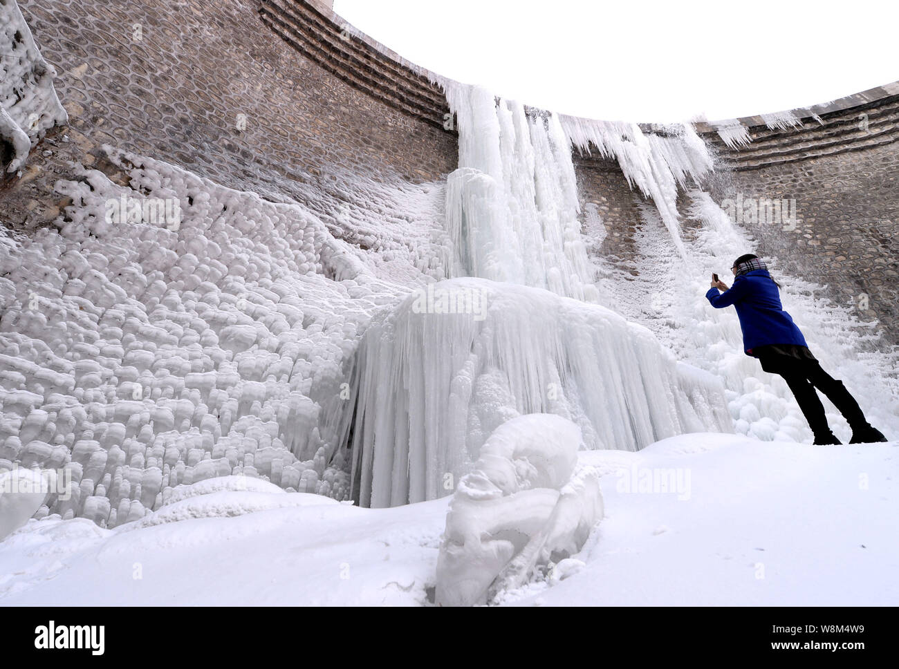 A visitor takes photos of silver thaw at a reservoir in Beijing, China ...