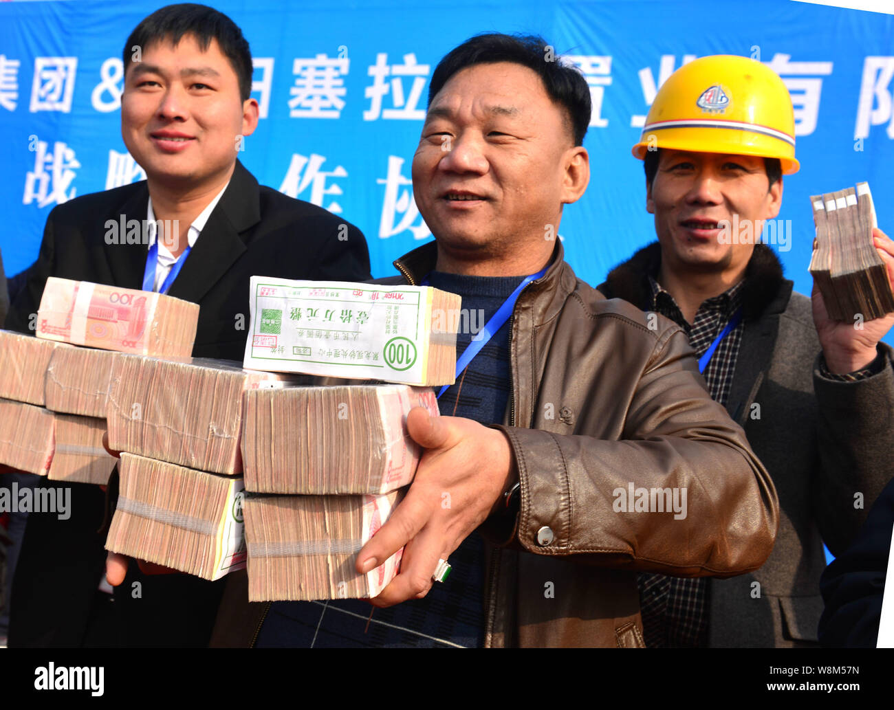 Chinese migrant workers show bundles of salaries at the construction ...
