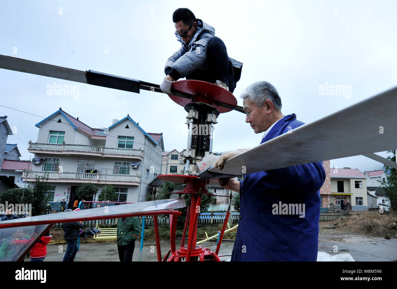 Chinese villager Jiang Changgen, bottom, and his son install propeller ...