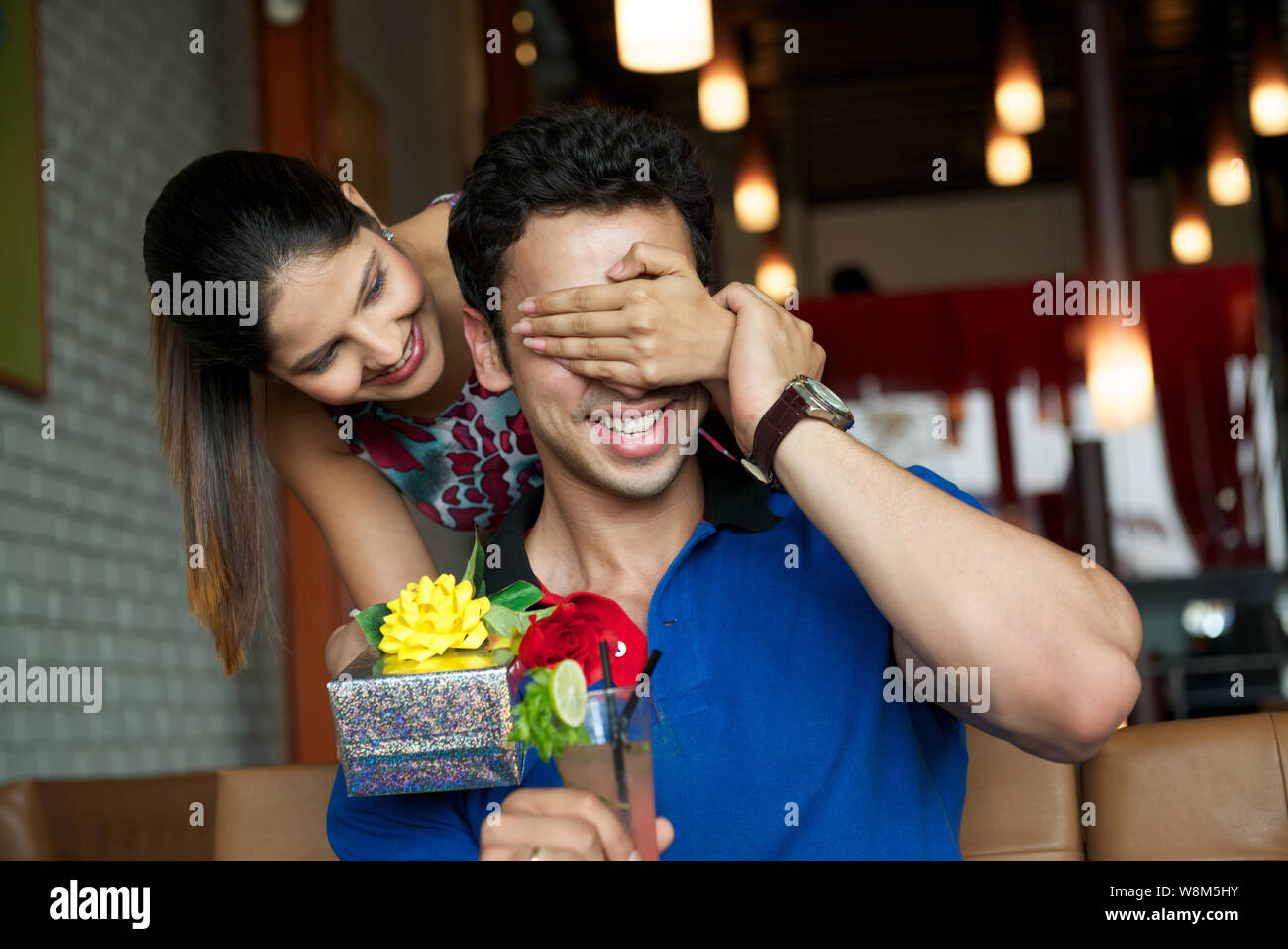 Woman giving a surprise gift to her boyfriend Stock Photo - Alamy