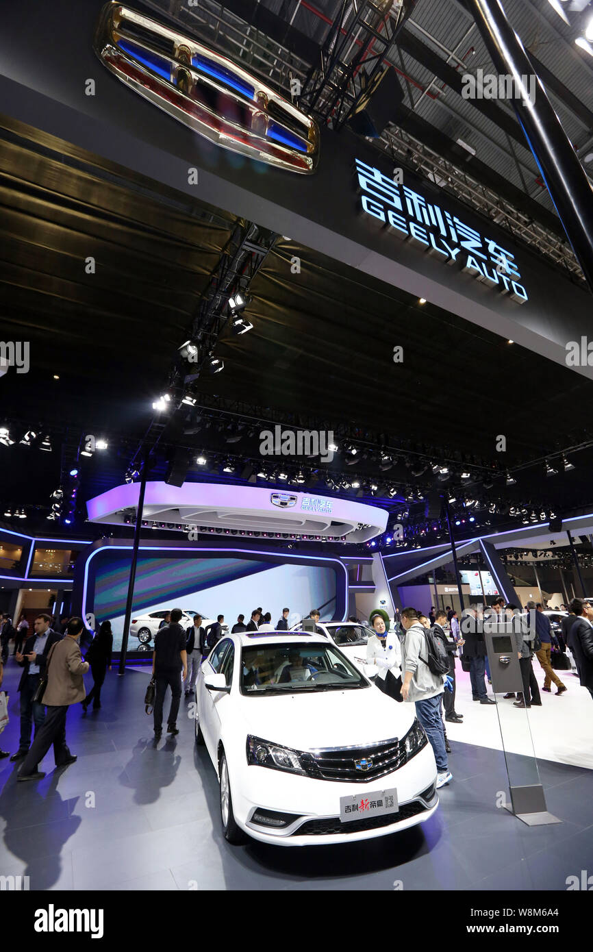 --FILE--Visitors try out or look at Geely cars on display during the ...