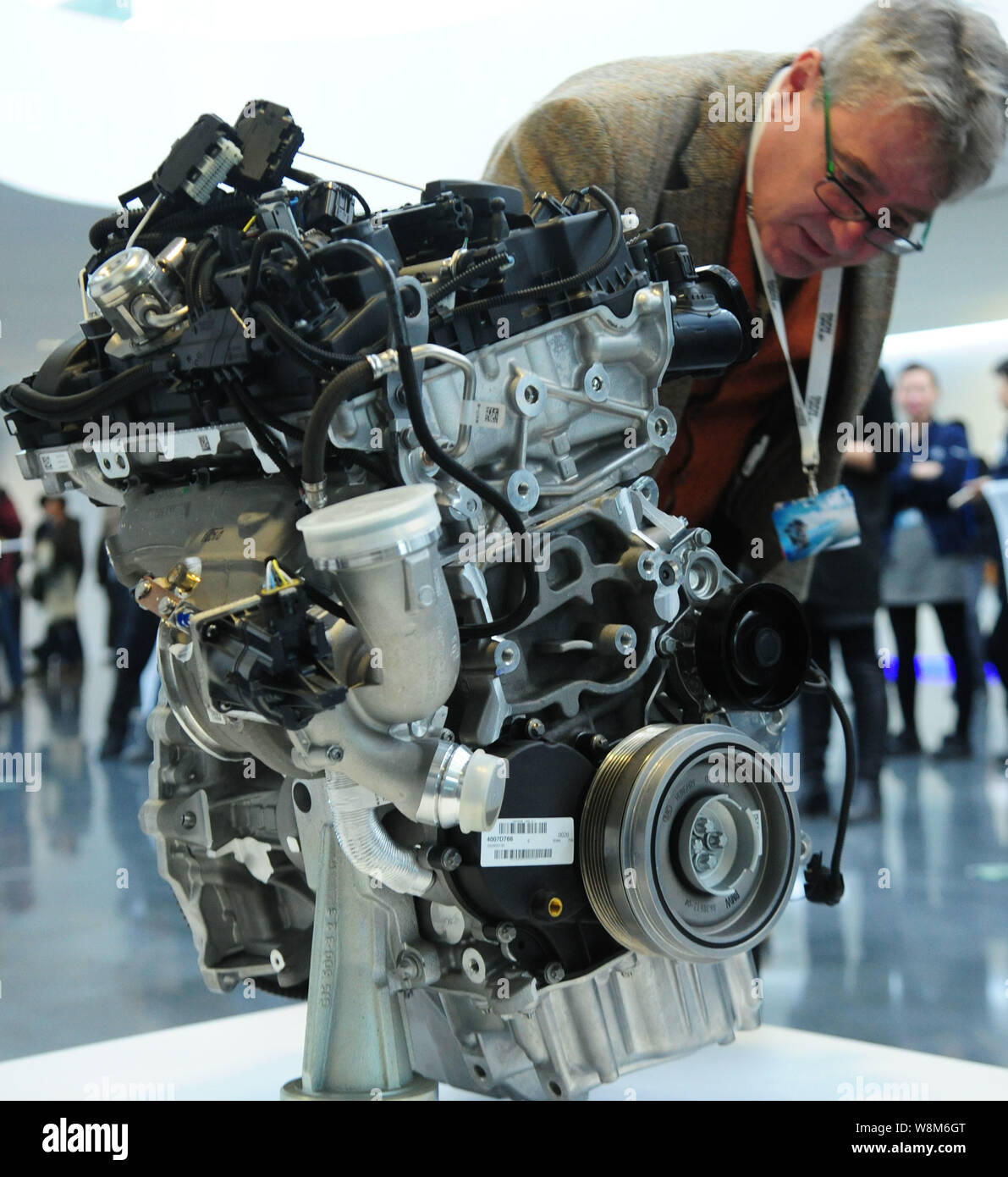 A visitor looks at a car engine during the opening ceremony of the new ...