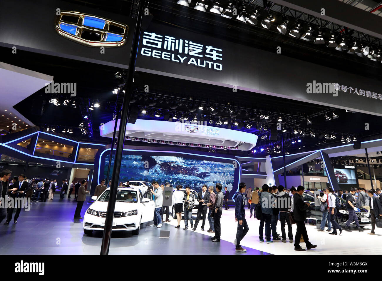 --FILE--Visitors try out or look at Geely cars on display during the ...