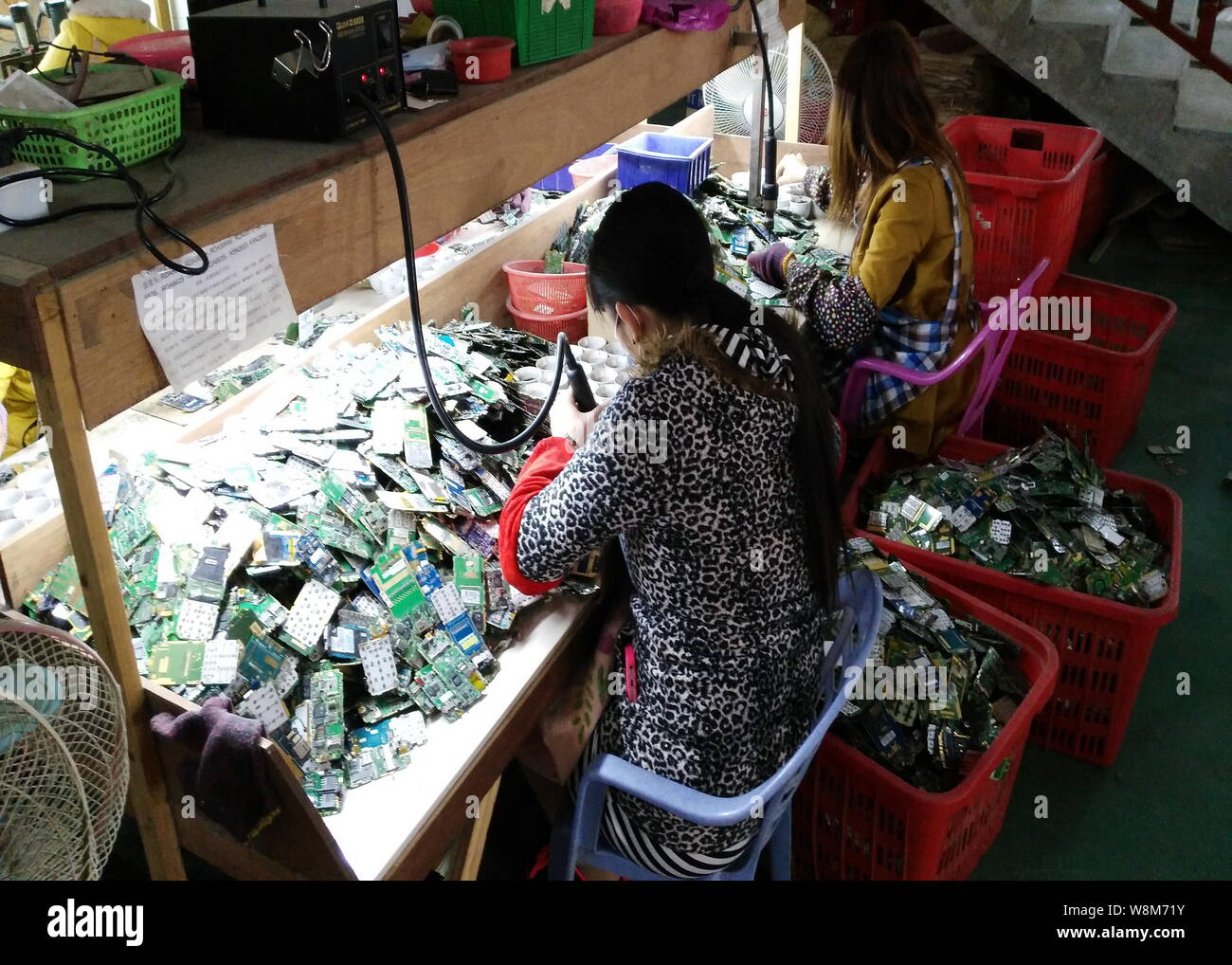 Female Chinese workers remove components from circuit boards of mobile ...