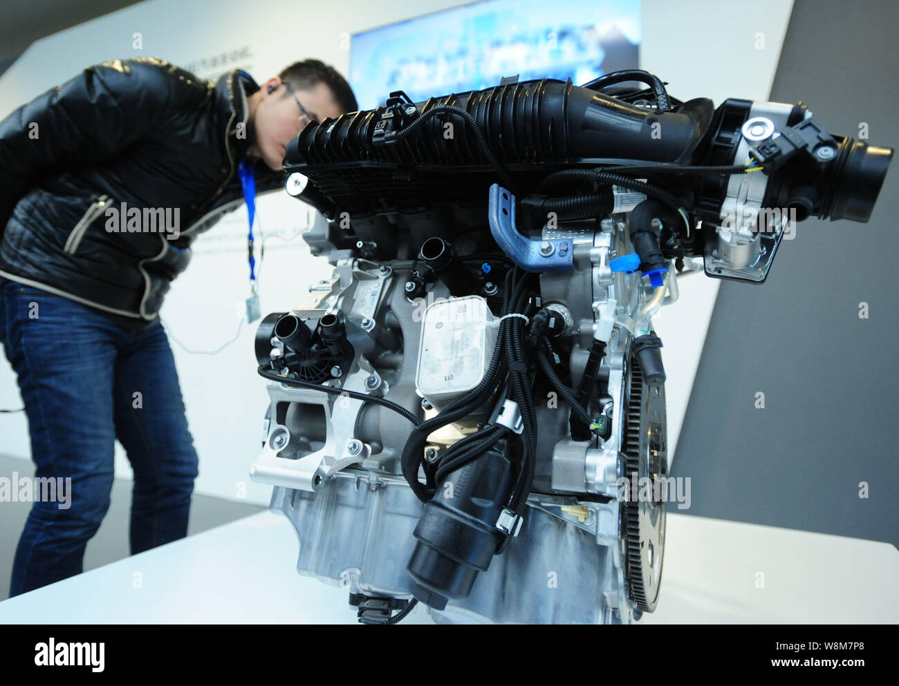 A visitor looks at a car engine during the opening ceremony of the new ...