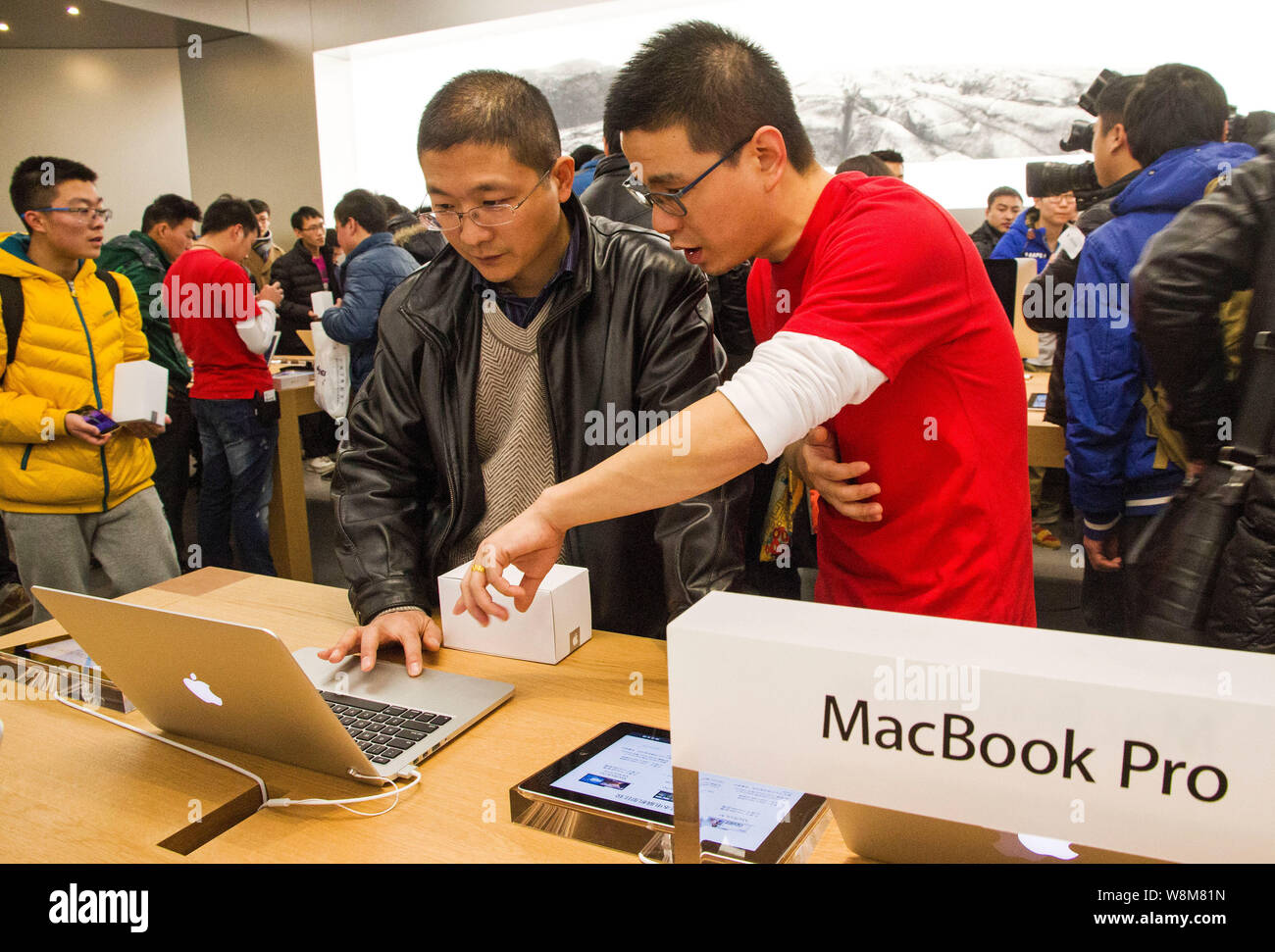 --FILE--A Chinese employee, right in red, assists a customer to try out ...