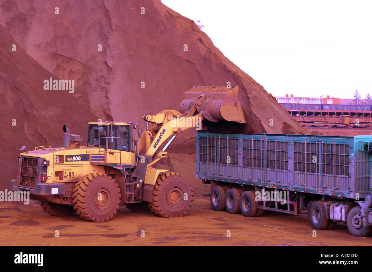 --FILE--A wheel loader loads a truck with iron ore on a quay at the ...