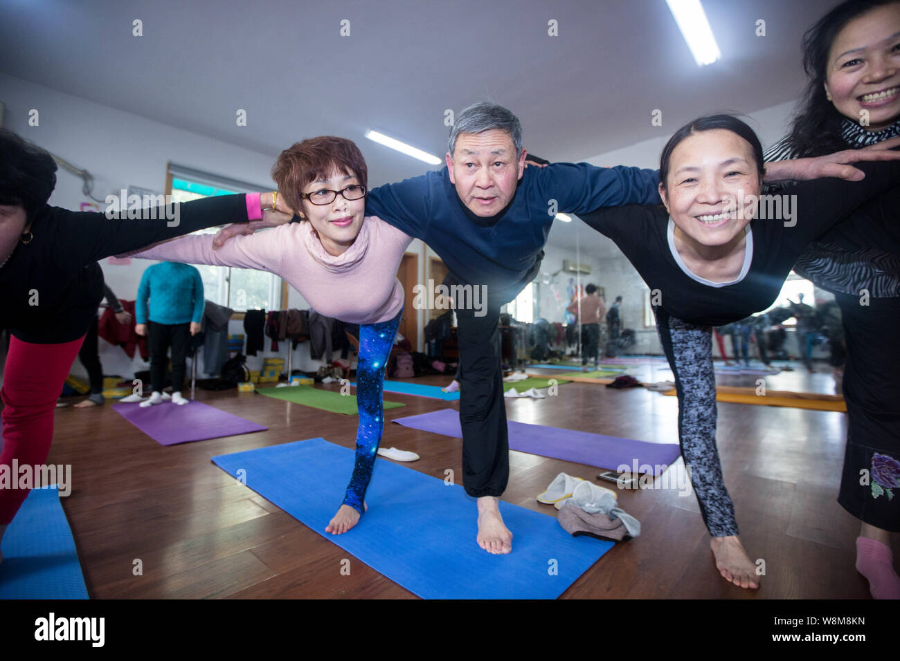 72-year-old Chinese man Le Mingchao, center, performs yoga with ...