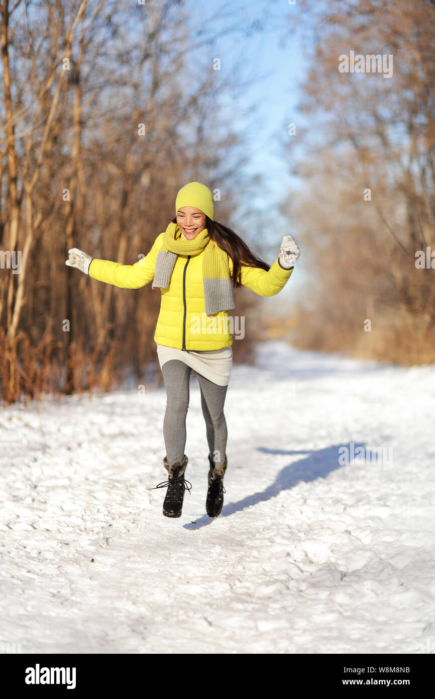 Happy girl running in snow winter landscape. Joyous young Asian woman ...
