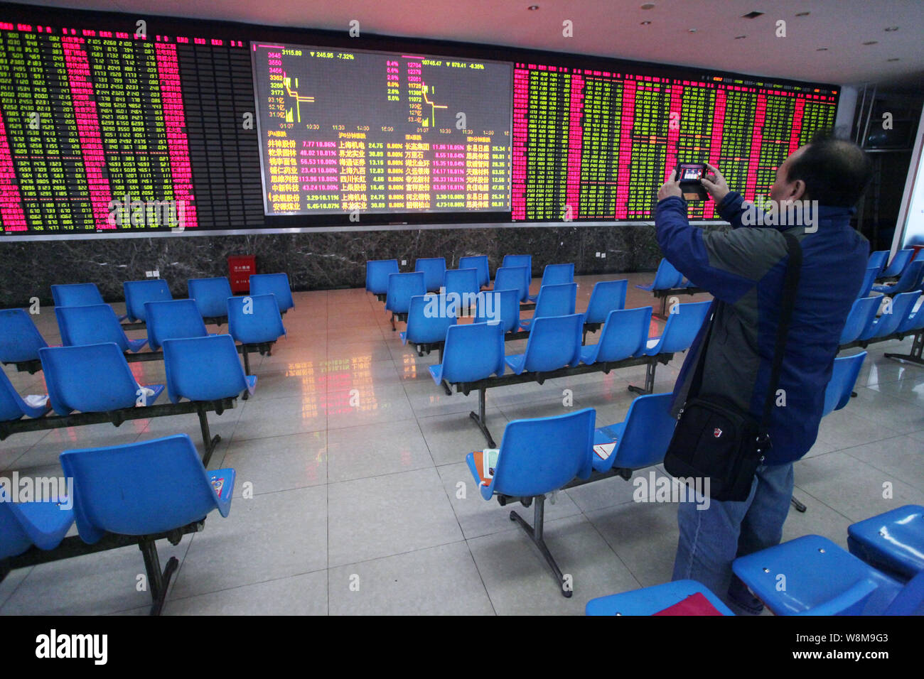 A Chinese investor takes pictures of an electronic display showing ...